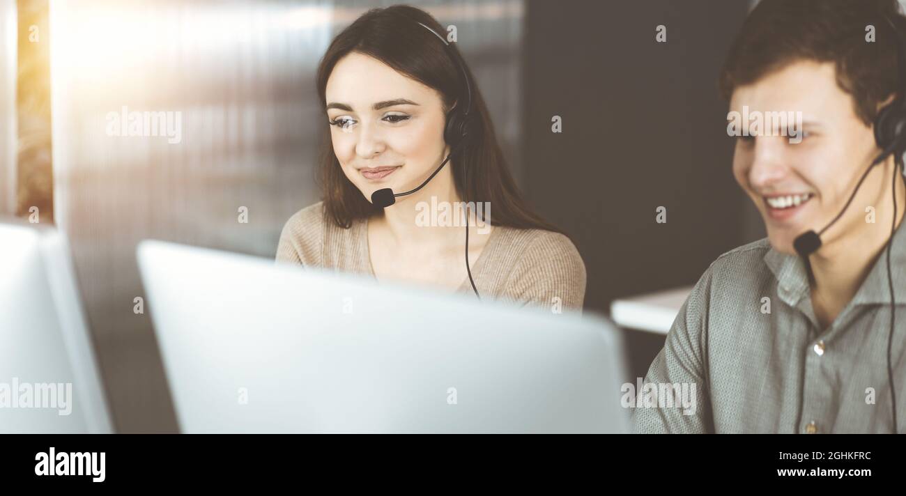 Call center operators at work. Two young people in headsets are talking ...