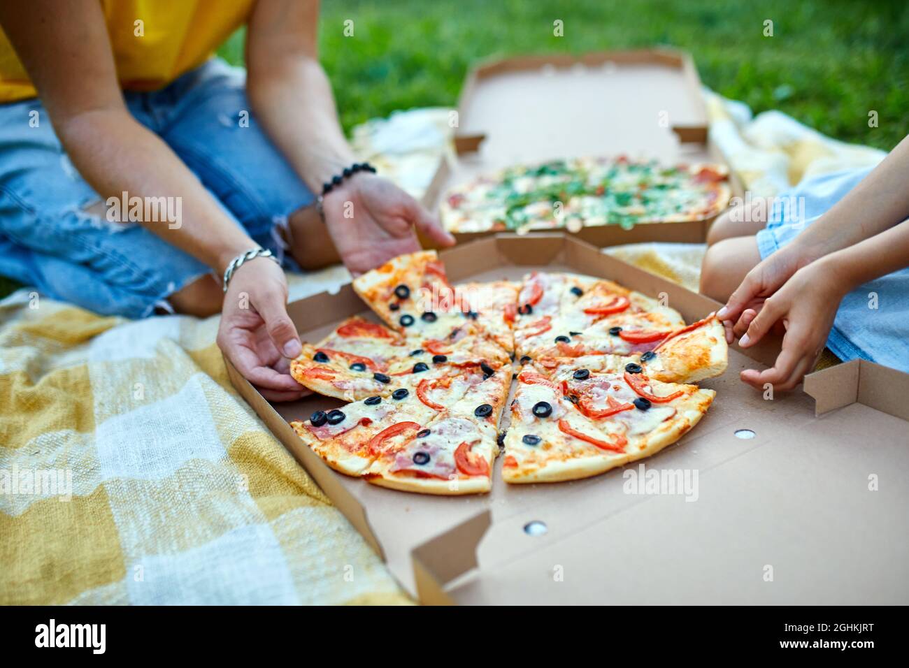 Sharing pizza, hands taking a piece of pizza from a box outdoor, family ...