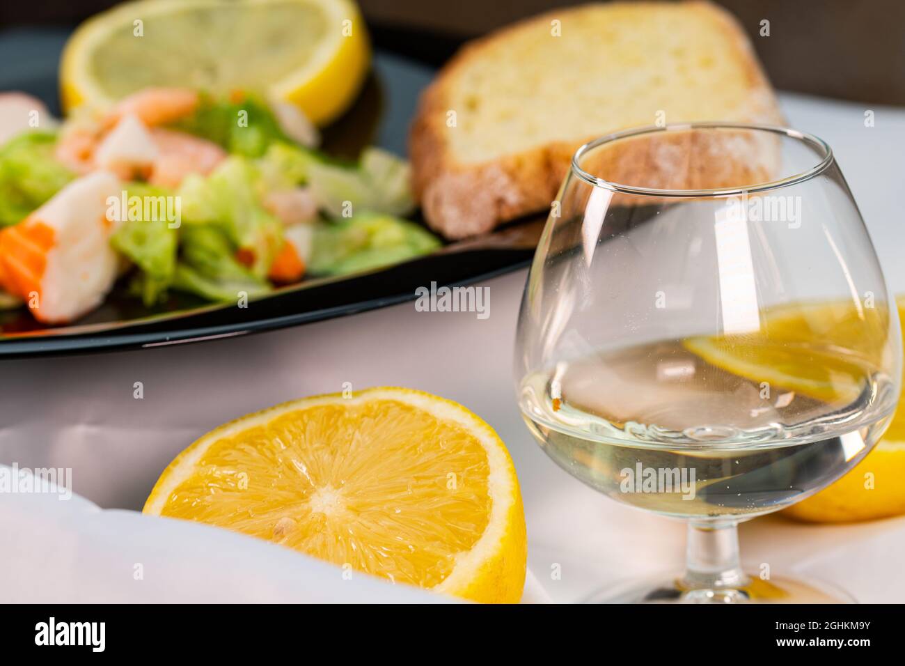a lemon split in half in front of a plate of fish with a glass of white ...