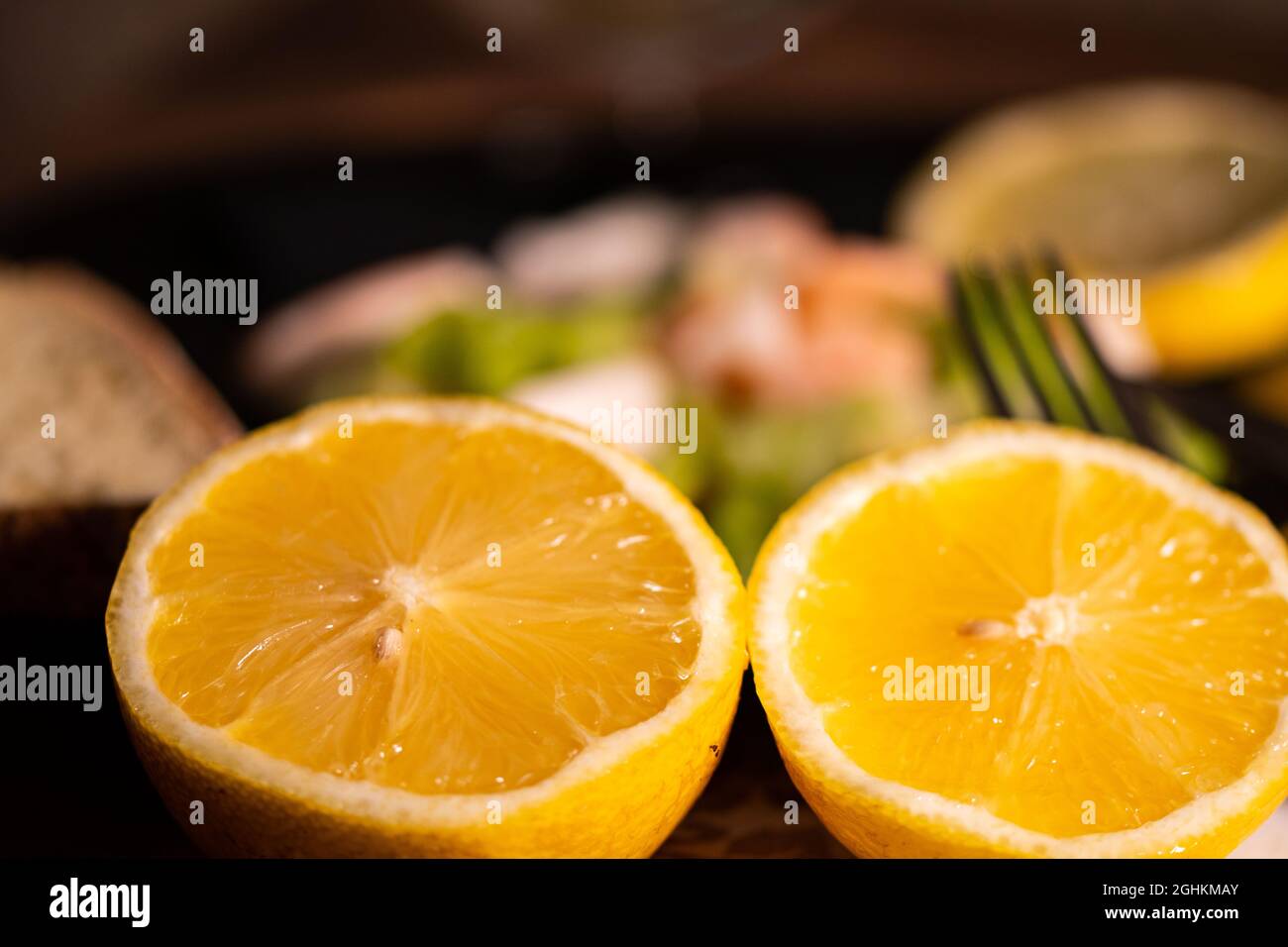 a lemon split in half in front of a plate of fish with a glass of white ...