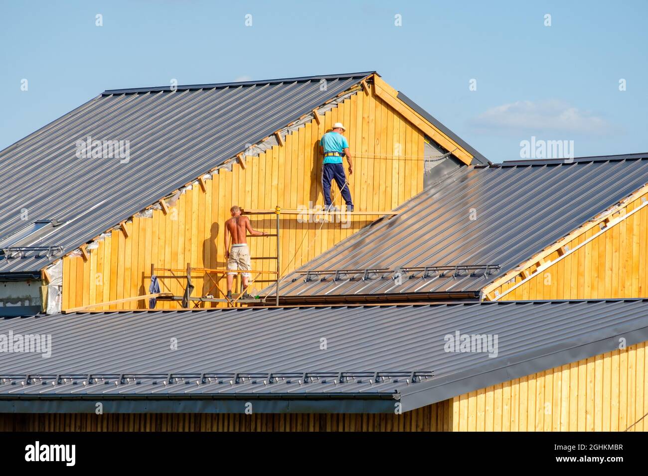 Workers on the roof of a country house on a sunny day. Roofing Stock ...
