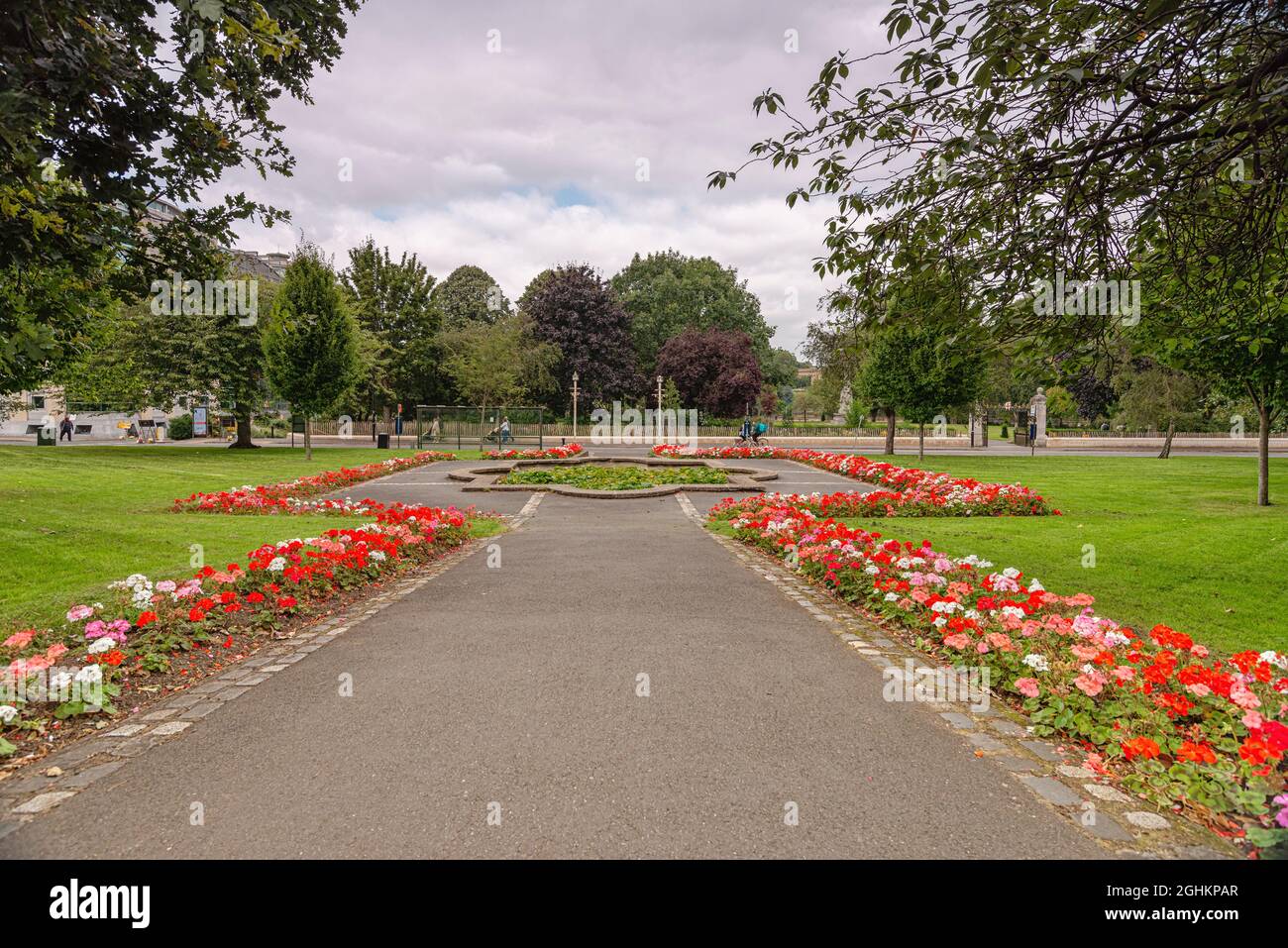 A public space consisting of colourful flower beds, and lawns. A path ...