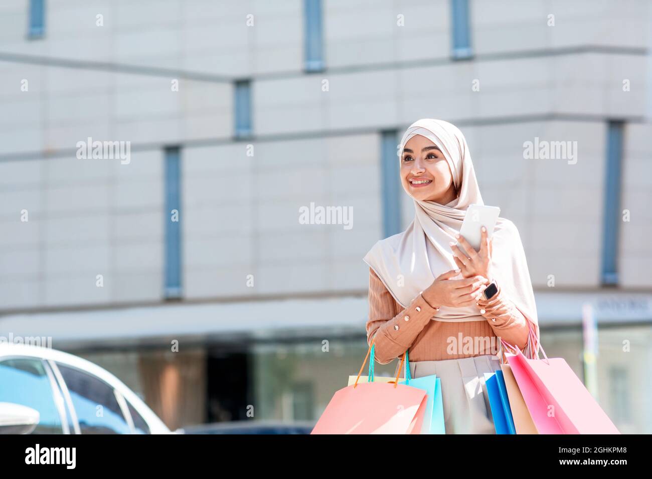 Smiling emotional millennial arab lady in hijab with a lot of packages ...