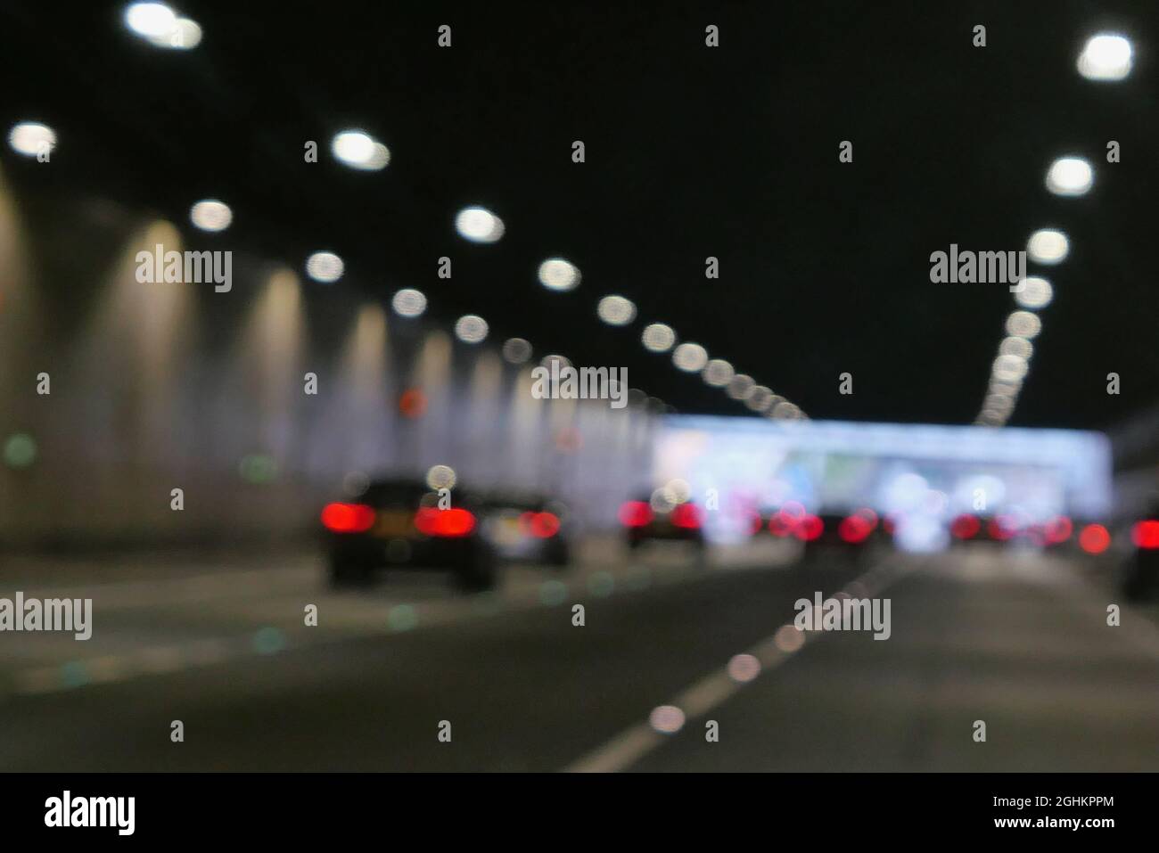 Blurred image of red rear car lights and overhead white lights Stock ...