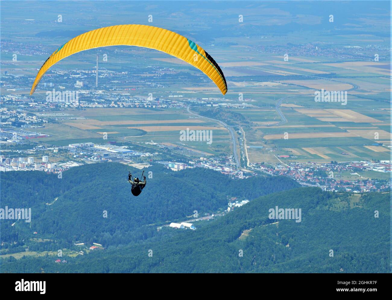 Aerial view of a person paragliding in the blue sky over a city Stock ...