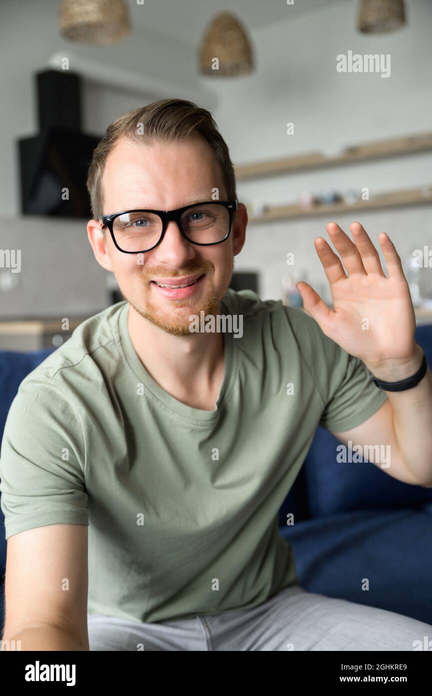 A cheerful guy is waving hello into webcam, smiles and greeting. Video ...