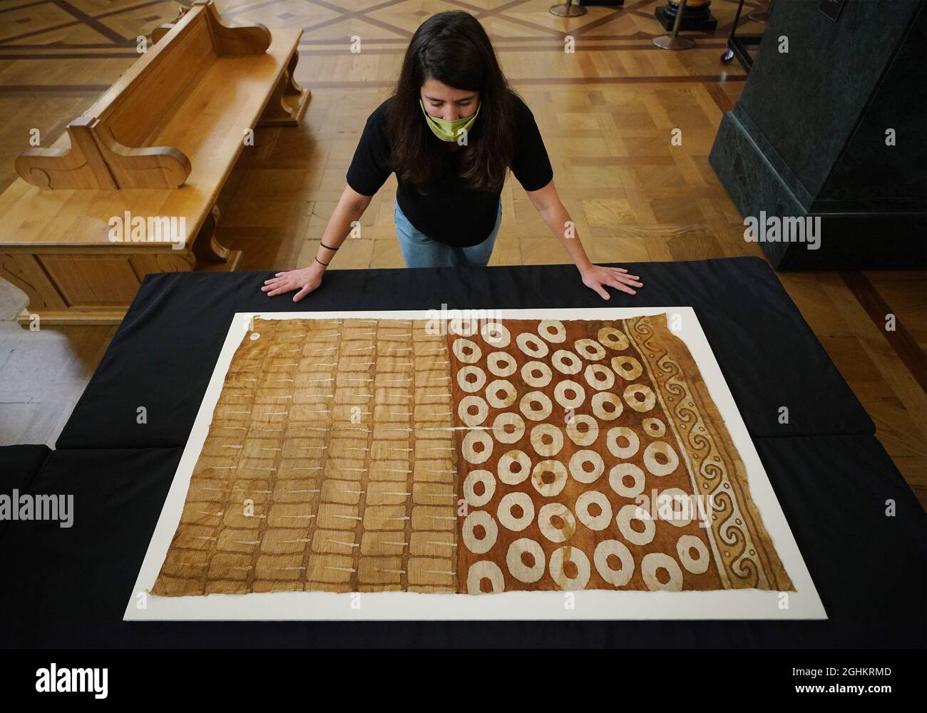 Collection manager Ana Carreira Galban stands over a cotton tunic ...
