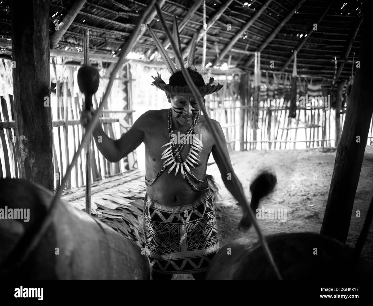 indigenous old man playing drums inside a traditional house in jungle ...