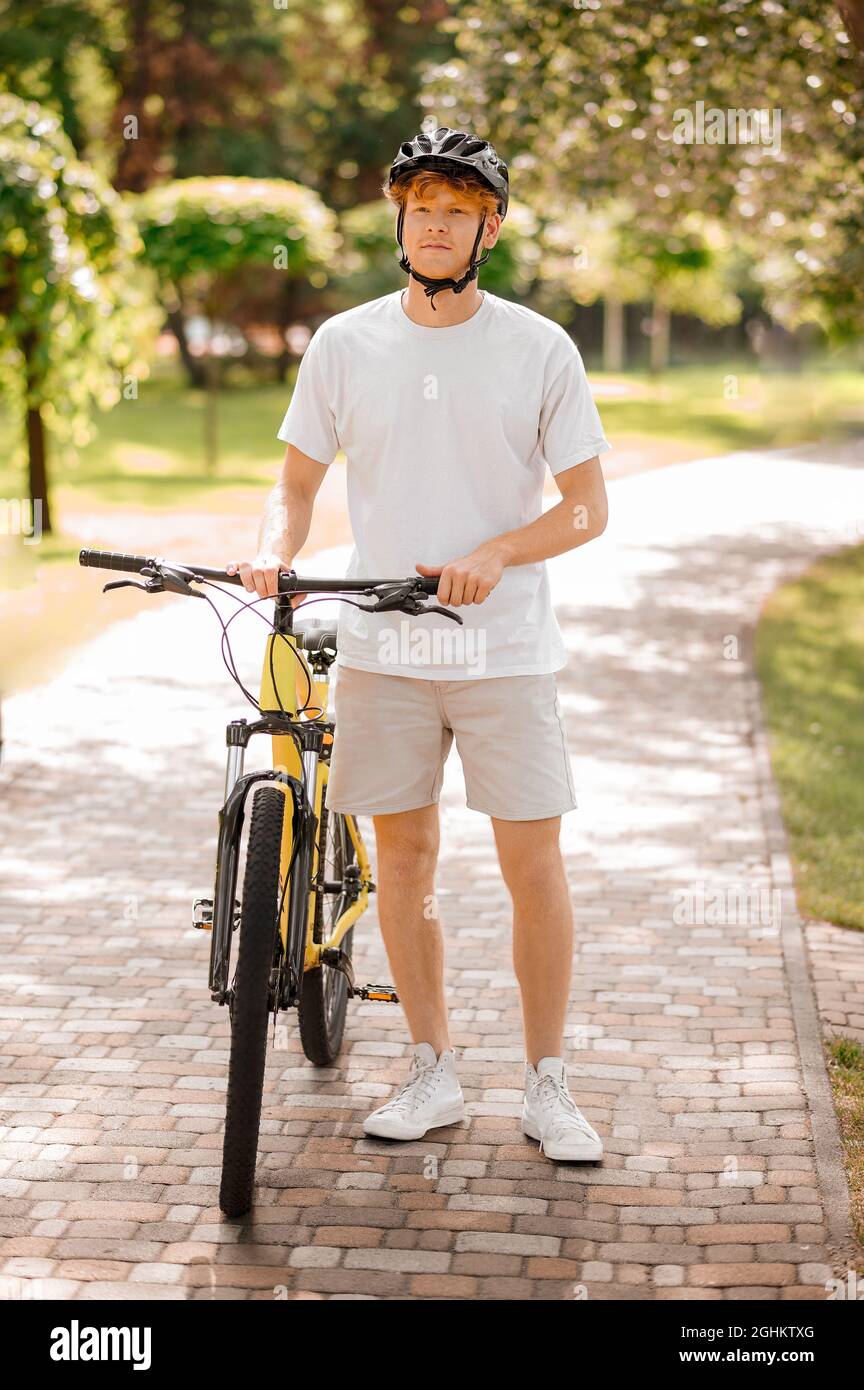 Guy in helmet with bike standing in park Stock Photo - Alamy