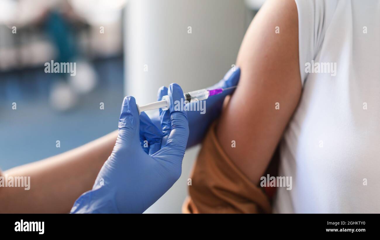 Young Woman Receiving Vaccine Injection Sitting With Doctor Indoor ...