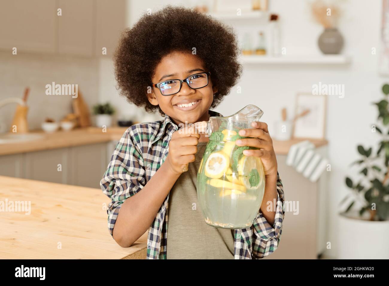 Cheerful little boy holding jug with homemade lemonade while standing ...