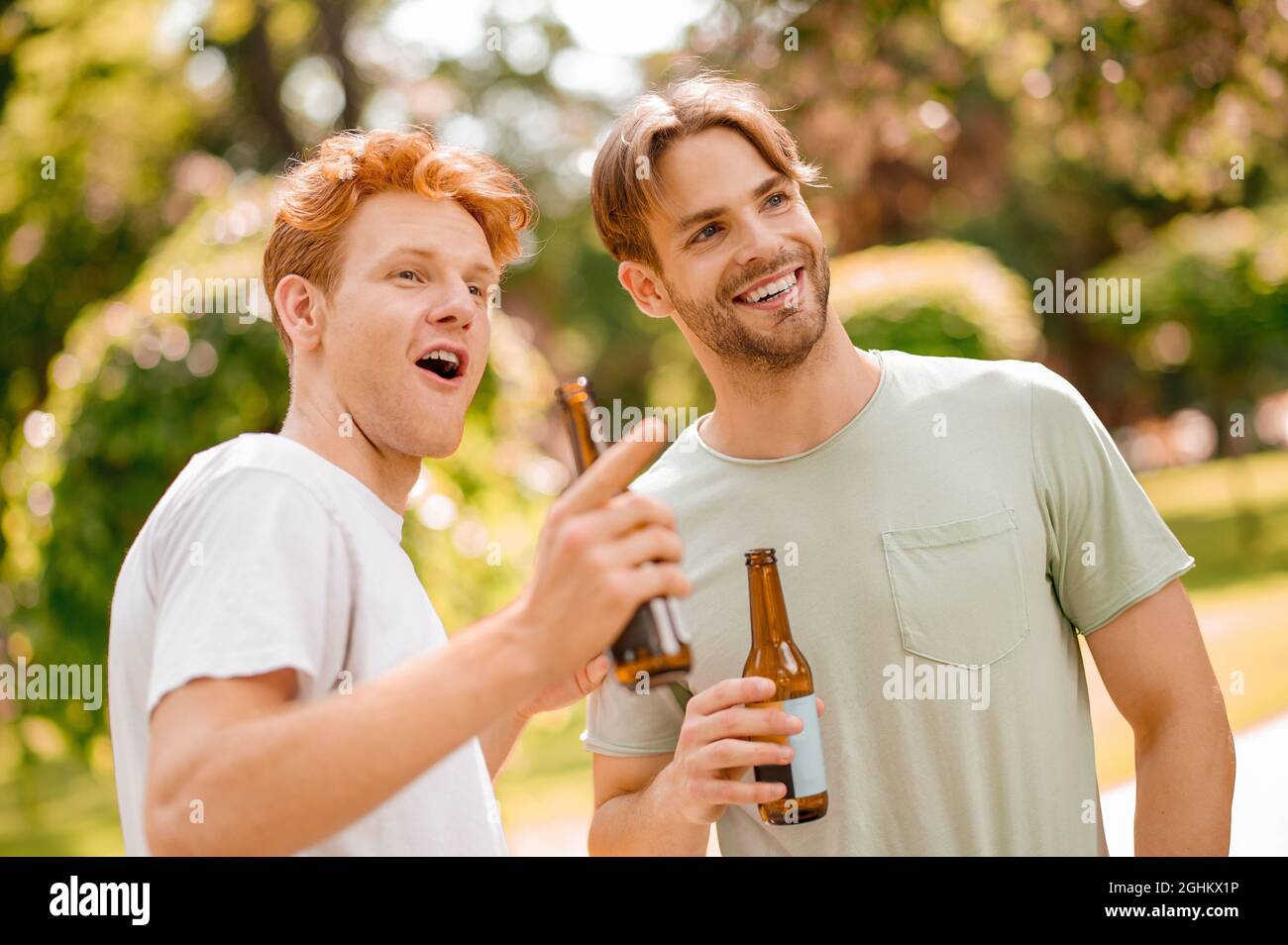 Smiling guys with bottles seeing something interesting Stock Photo - Alamy