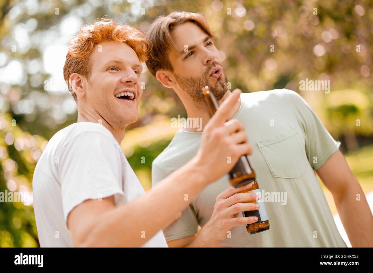 Guys with bottles watching with interest in park Stock Photo - Alamy