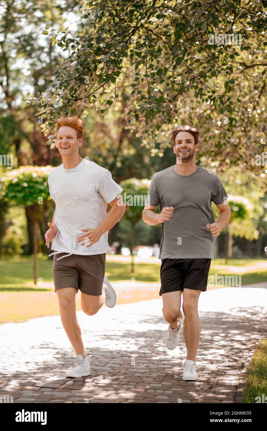 Two smiling friends running in park Stock Photo - Alamy