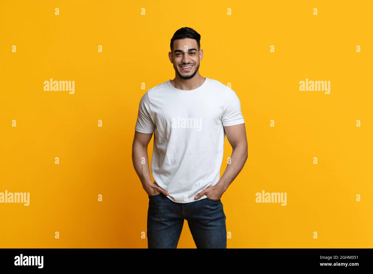 Hot arabic guy smiling on yellow studio background Stock Photo - Alamy