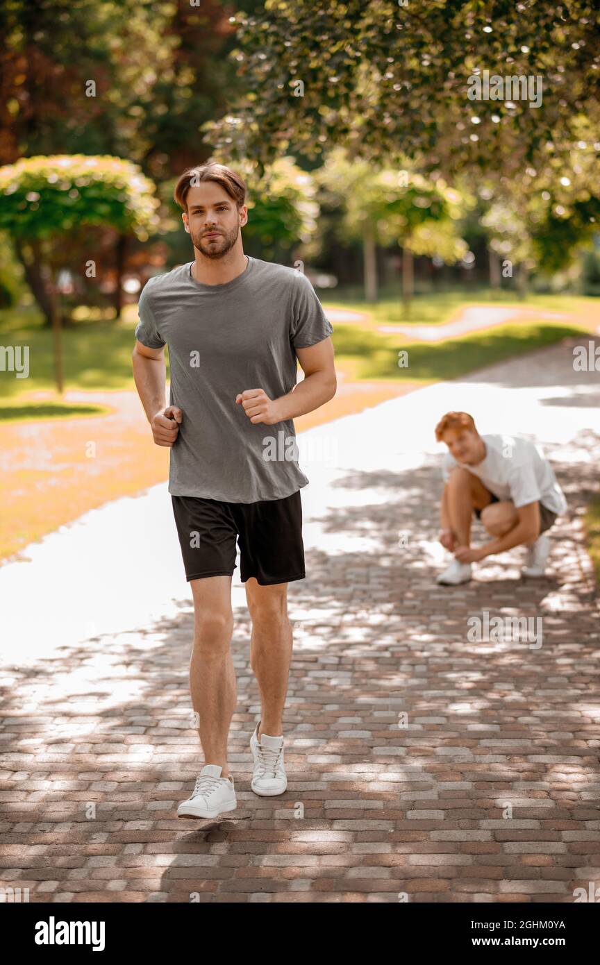 Running guy marathon runner and straggling friend Stock Photo - Alamy