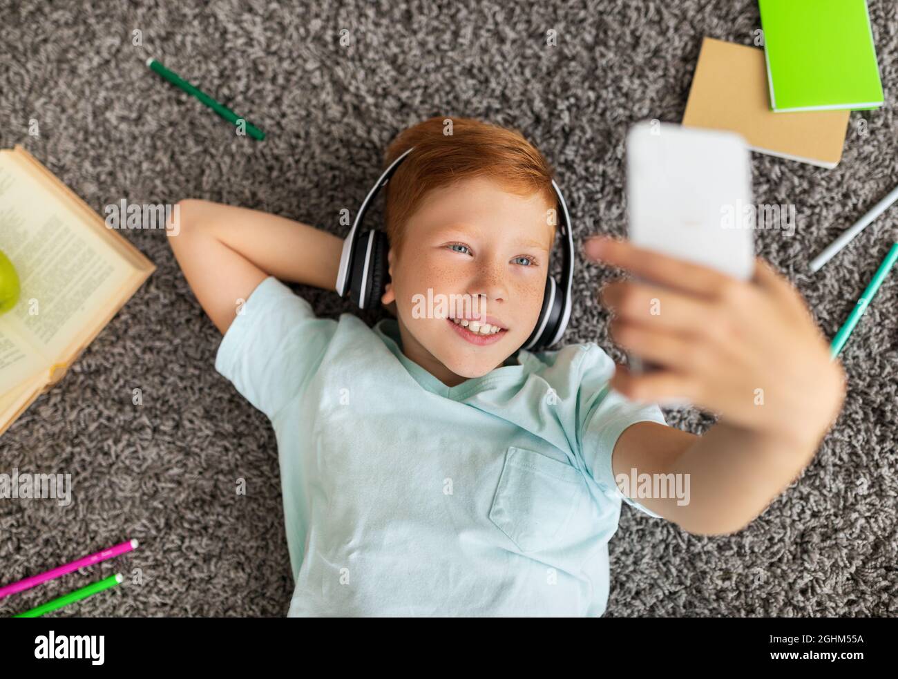 Cute kid using headset and cellphone while doing homework Stock Photo ...