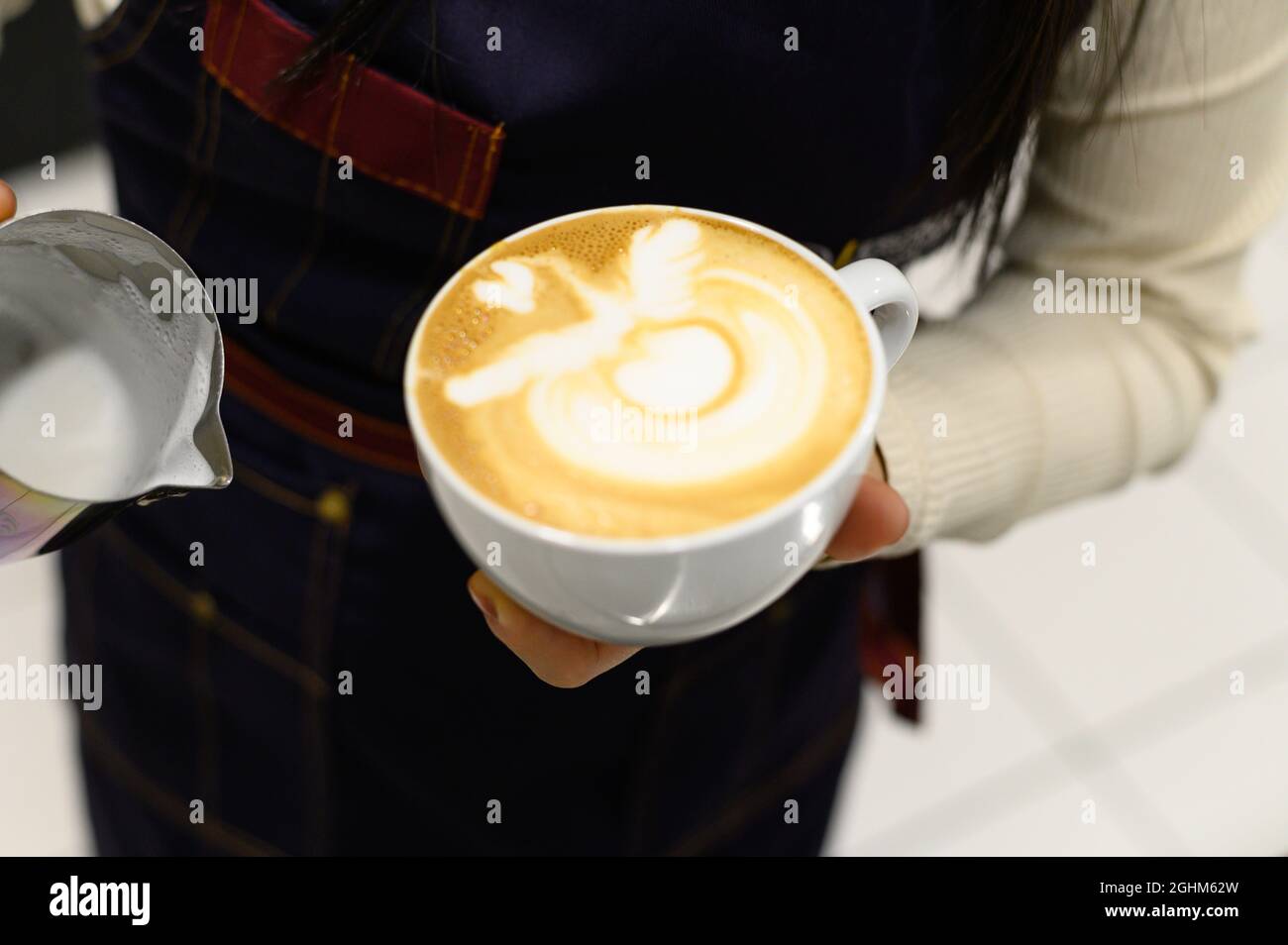 Hands of a young barista making coffee latte art Stock Photo - Alamy