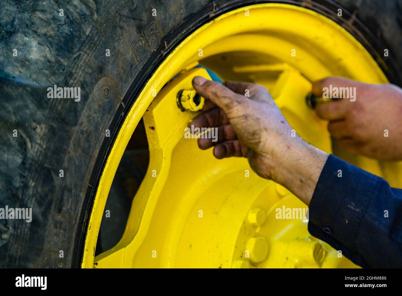 Putting a yellow tractor wheel Stock Photo - Alamy