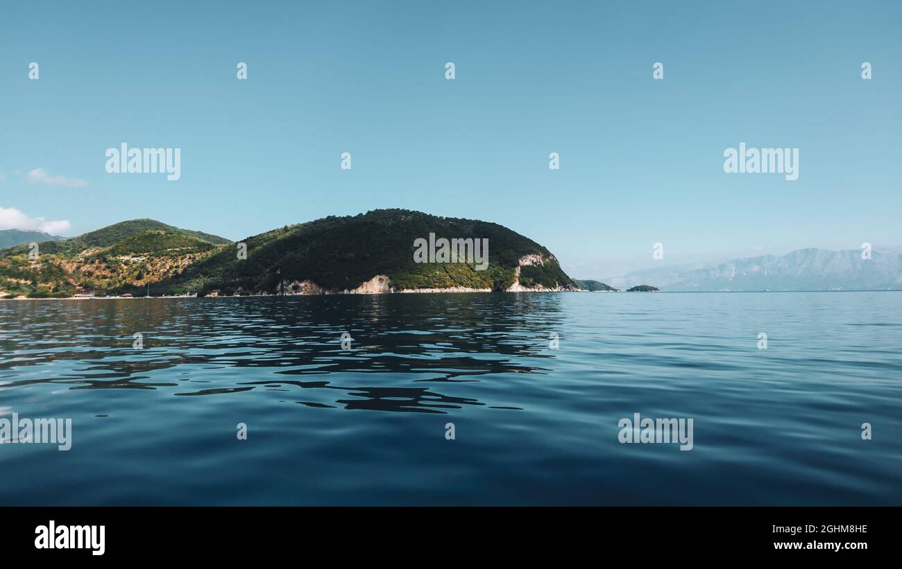 Blue clear calm Ionian Sea water with nice reflection and scenic green ...