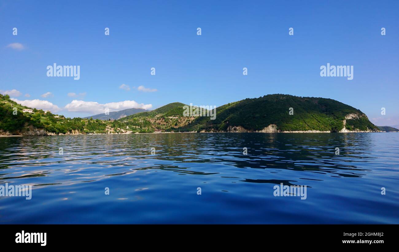 Blue clear calm Ionian Sea water with nice reflection and scenic green ...