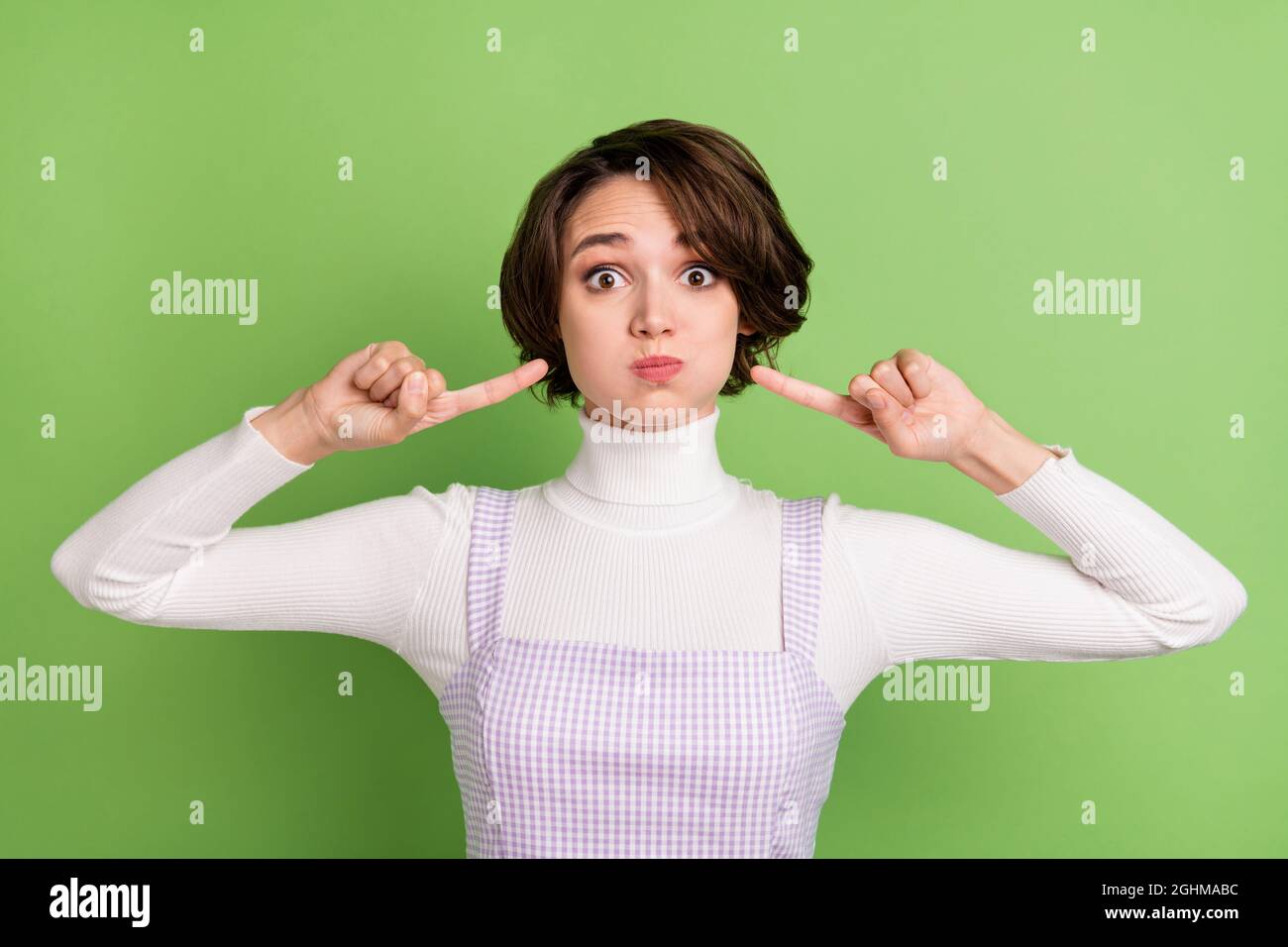 Photo portrait pretty woman pointing finger on cheeks hold breath ...