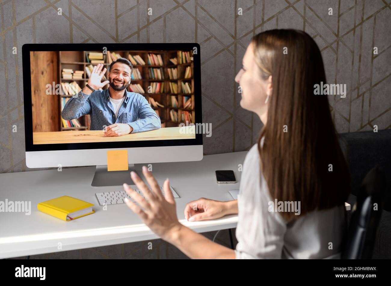 A friendly female office worker in casual wear, sitting at the desk in ...