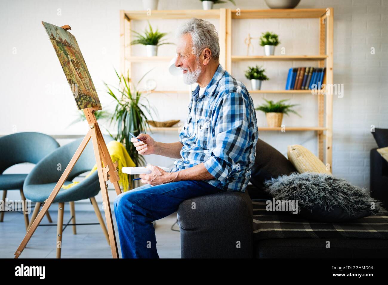 Happy retired man painting on canvas for fun at home Stock Photo - Alamy