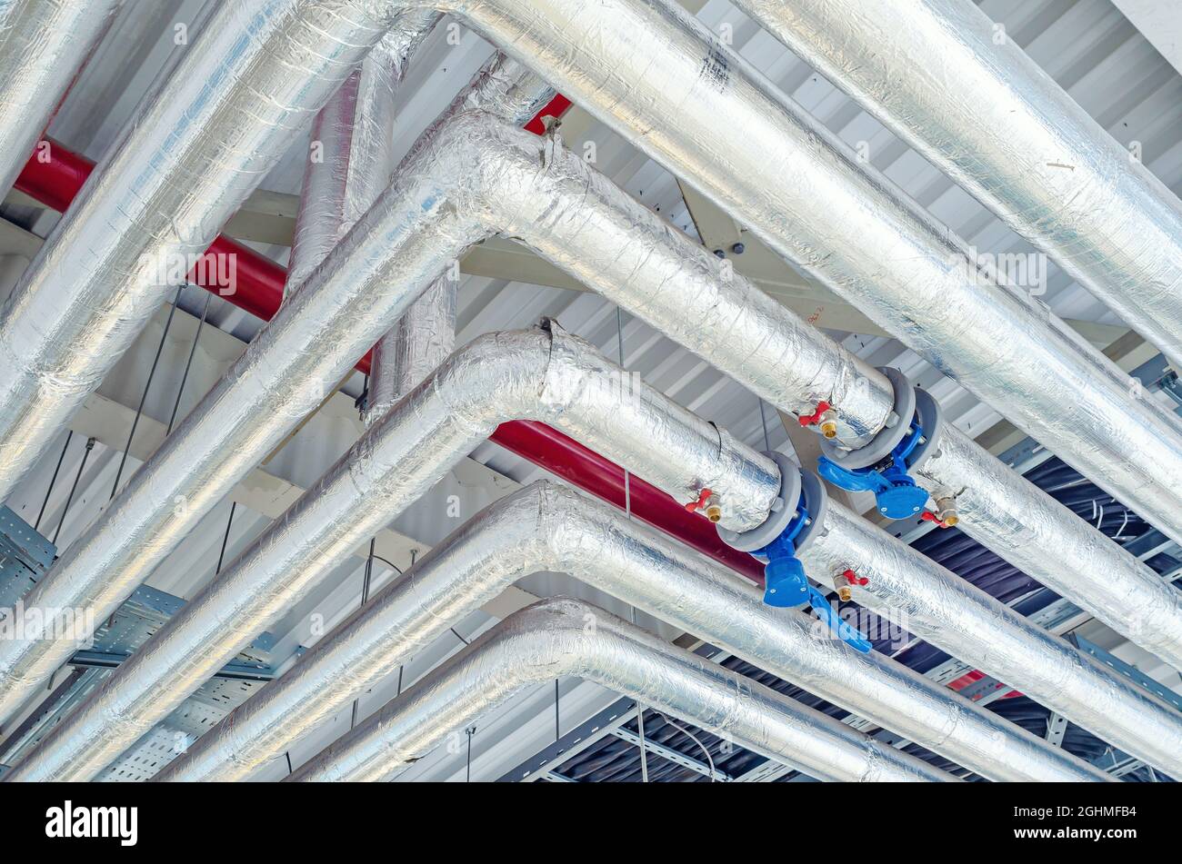 Metal pipes mounted under ceiling are covered with thermal insulation ...