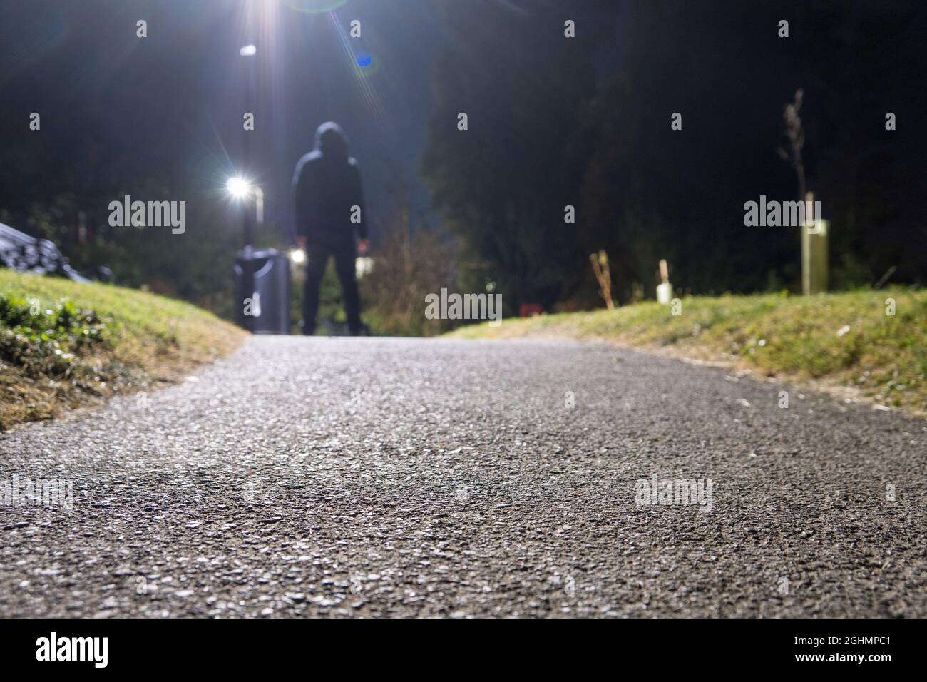Low angle of a mysterious hooded figure standing under a street light ...