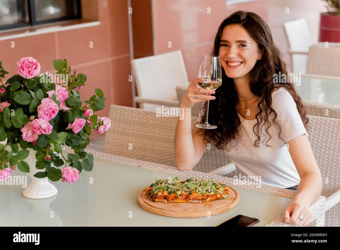 Girl with pinsa romana in cafe on summer terrace. Young woman eating pinsa and drinking wine ...