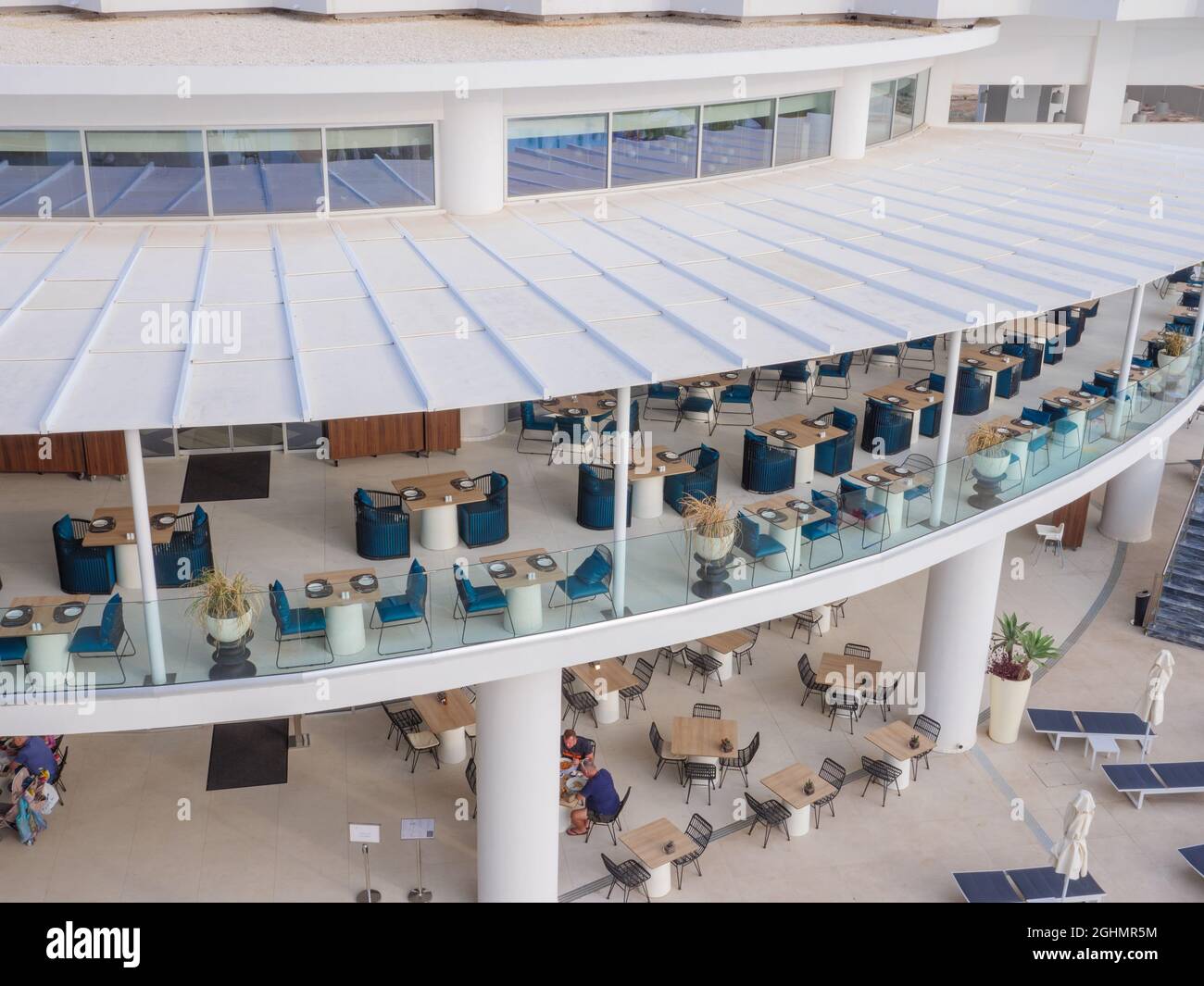 Open-air terrace hotel restaurant with wooden dining tables and blue ...