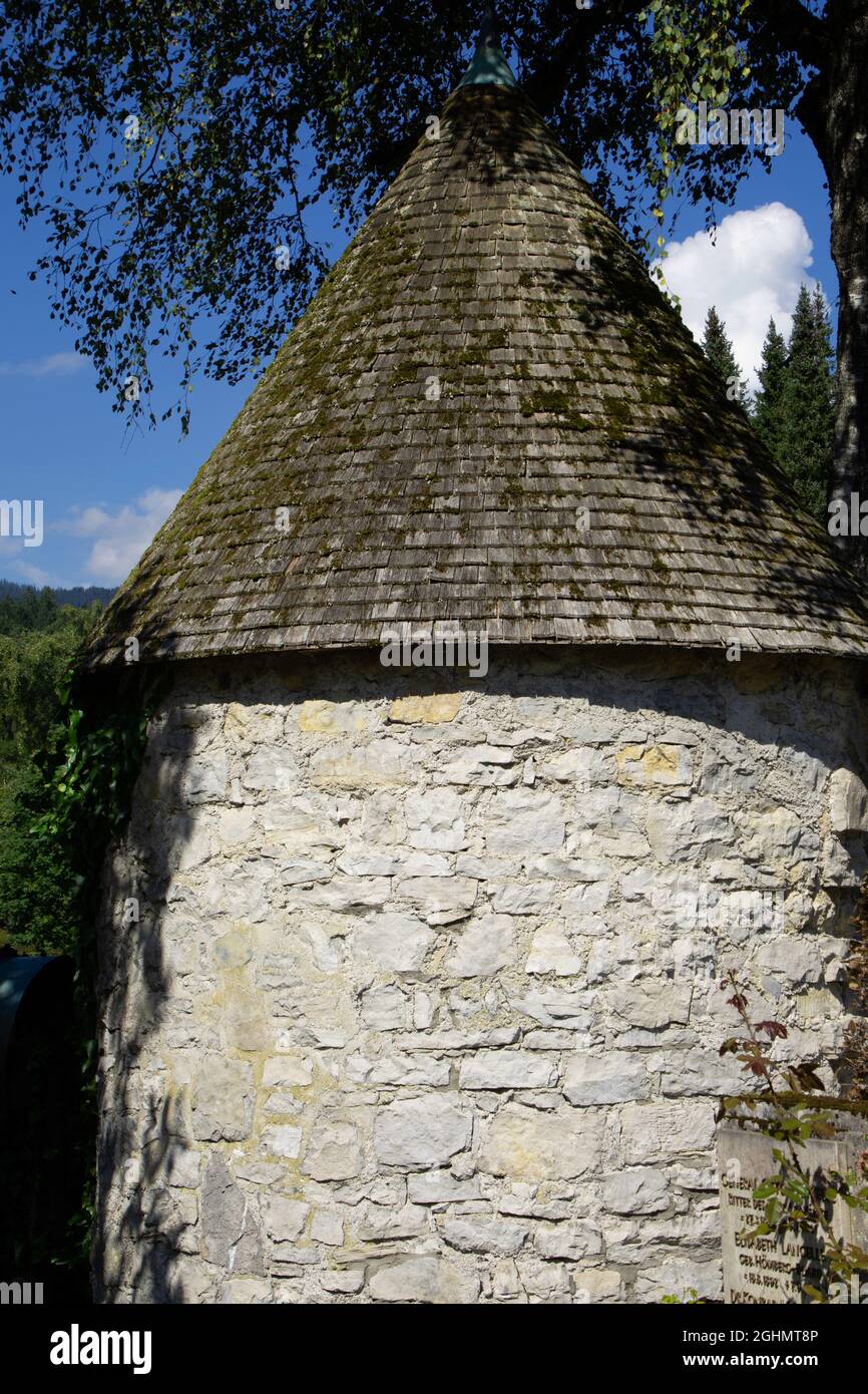 round stone house with old shingle roof in front of the bavarian summer ...