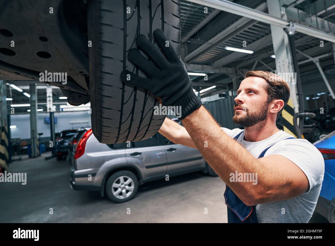 Worker of car repair removing wheel from auto Stock Photo - Alamy