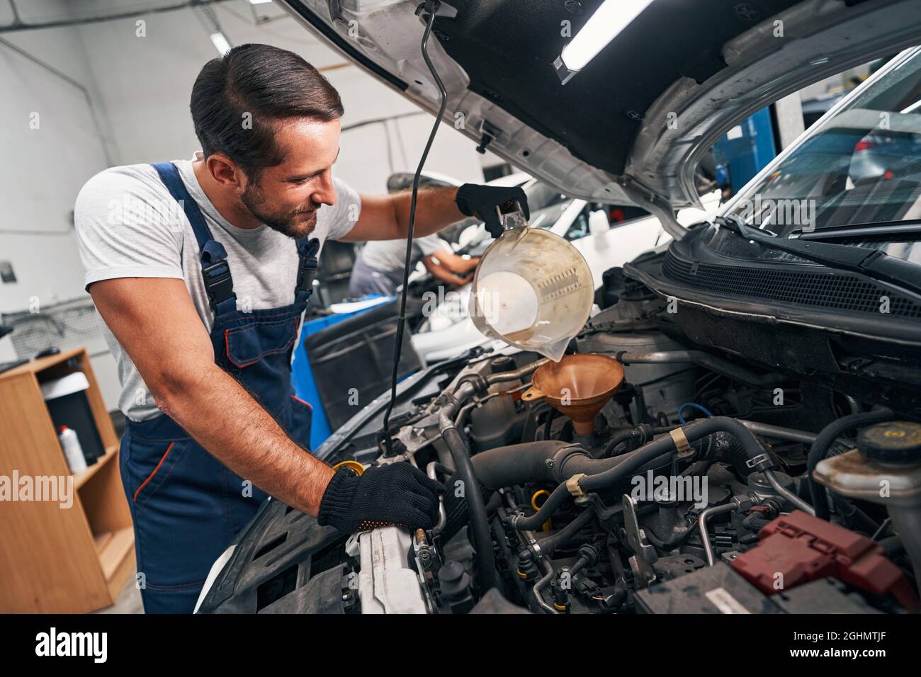 Pleased mechanic refilling oil into car engine Stock Photo - Alamy