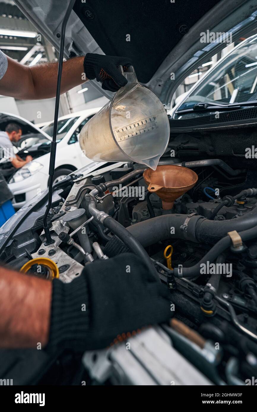 Worker turning over plastic cup while adding oil to engine Stock Photo ...