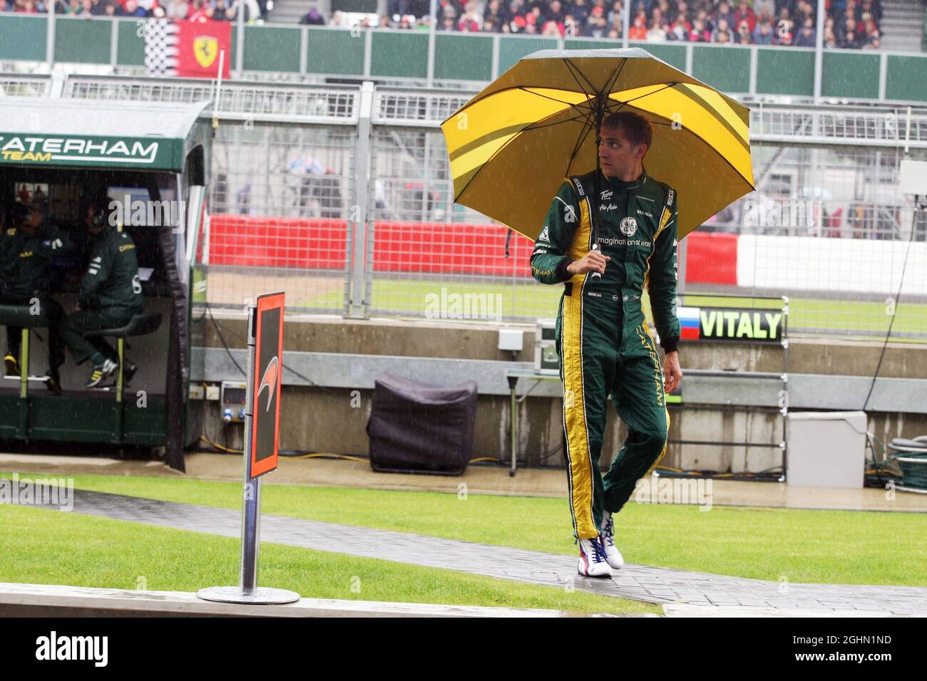 Vitaly Petrov (RUS) Caterham under the umbrella at the pit gantry. 06. ...