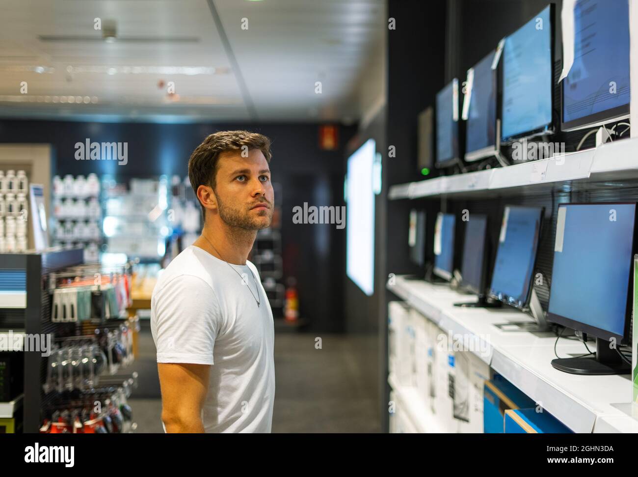 Side view of serious young bearded male customer standing near shelves ...