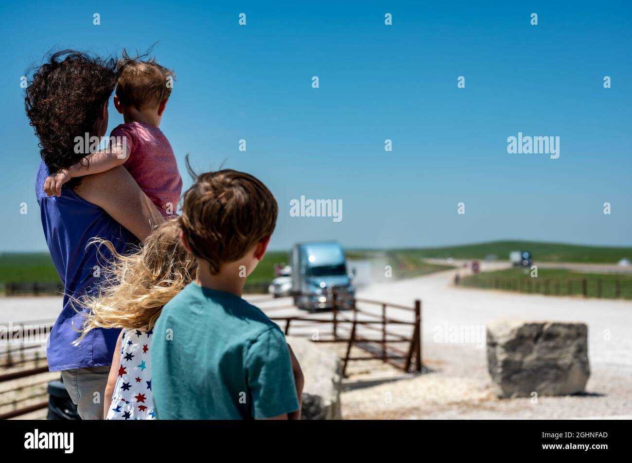 Mother and children looking into the distance while a semi truck comes ...