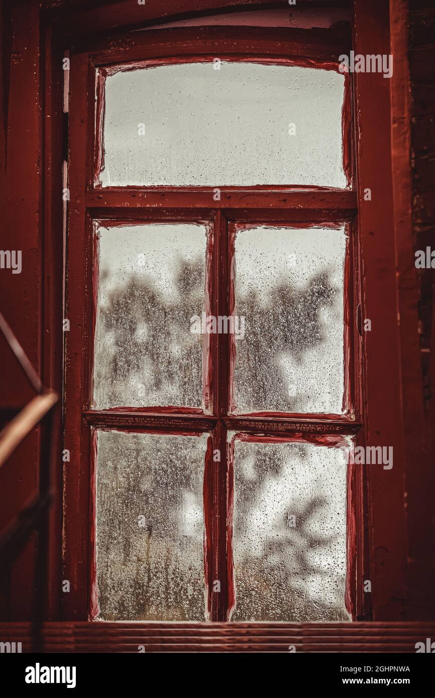 Red wooden window with raindrops on the glass. Old shabby window frame ...