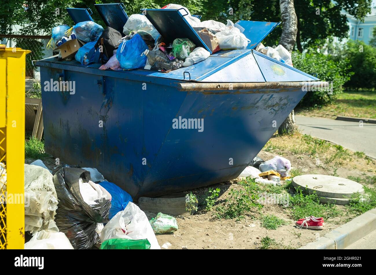 Bags of unsorted waste in and around an overflowing metal container in ...