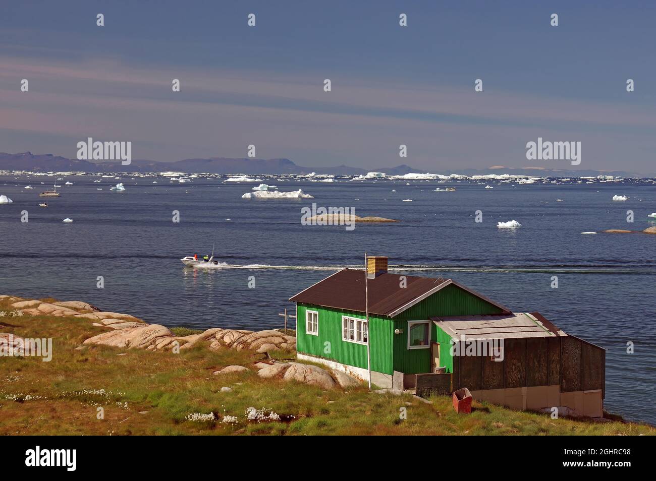 Simple dwelling house on the edge of an iceberg-covered bay, Ilulissat ...