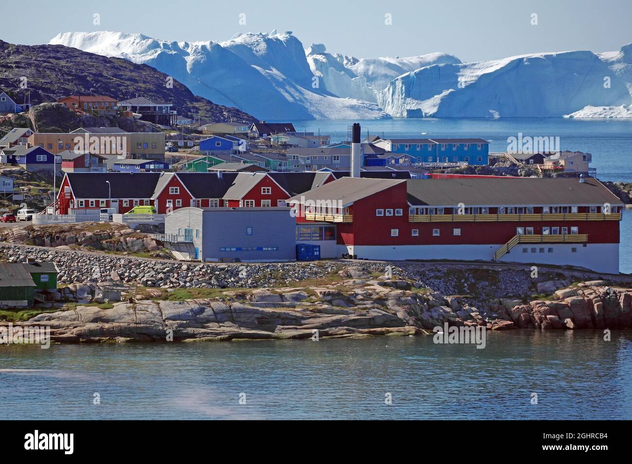 Buildings in front of icebergs, barren landscape, Disko Bay, Ilulissat ...