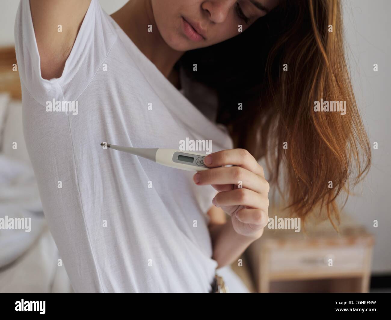 woman in white t-shirt checking the temperature with a thermometer ...