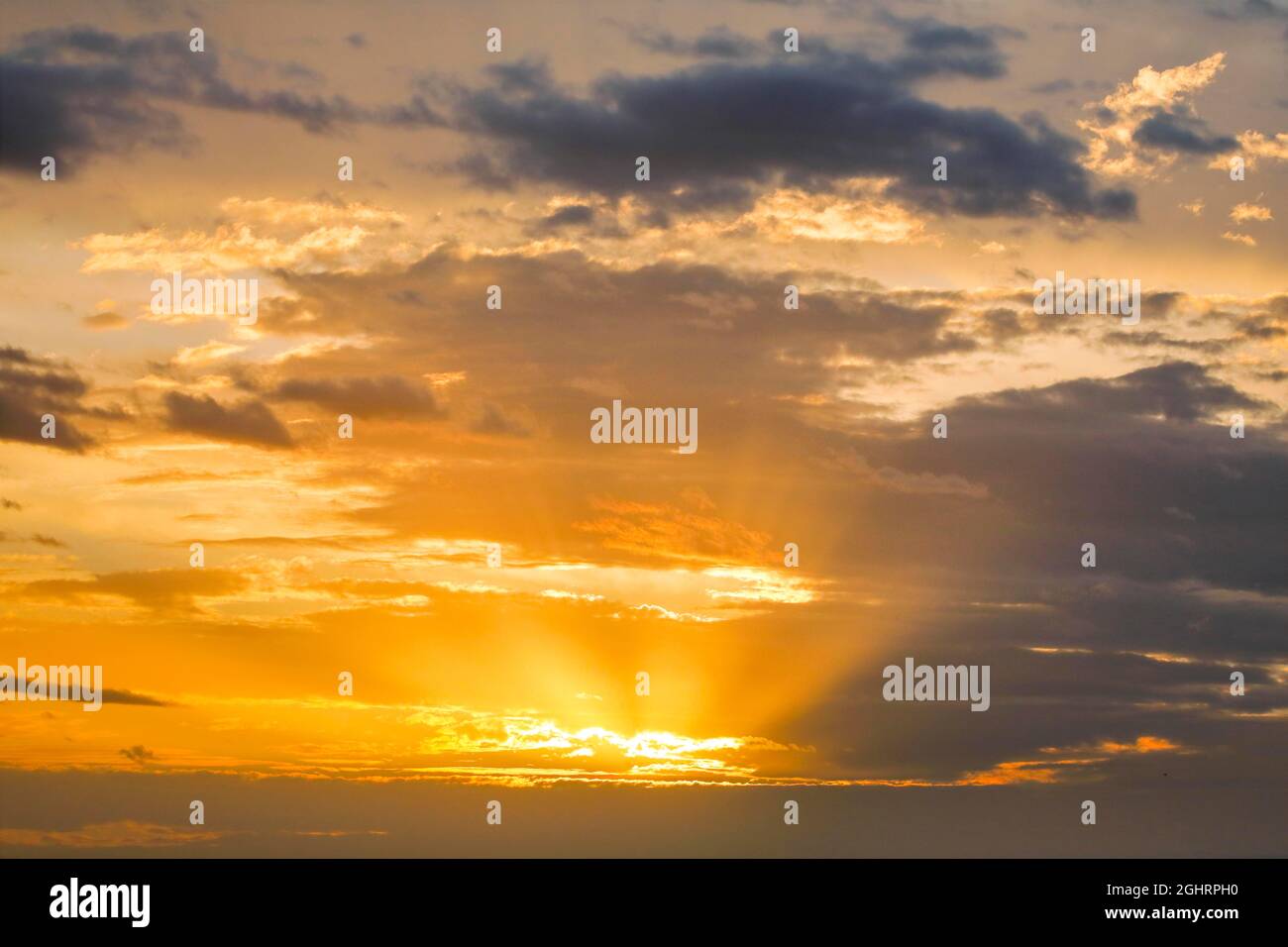 Golden sunbeams break through clouds at sunrise and form the Tyndall ...