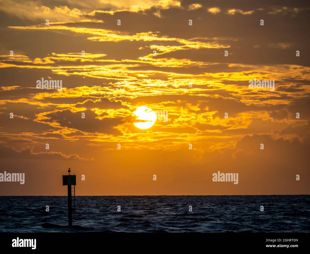 Orange yellow sky with clouds and sun near sunset over the Gulf of ...