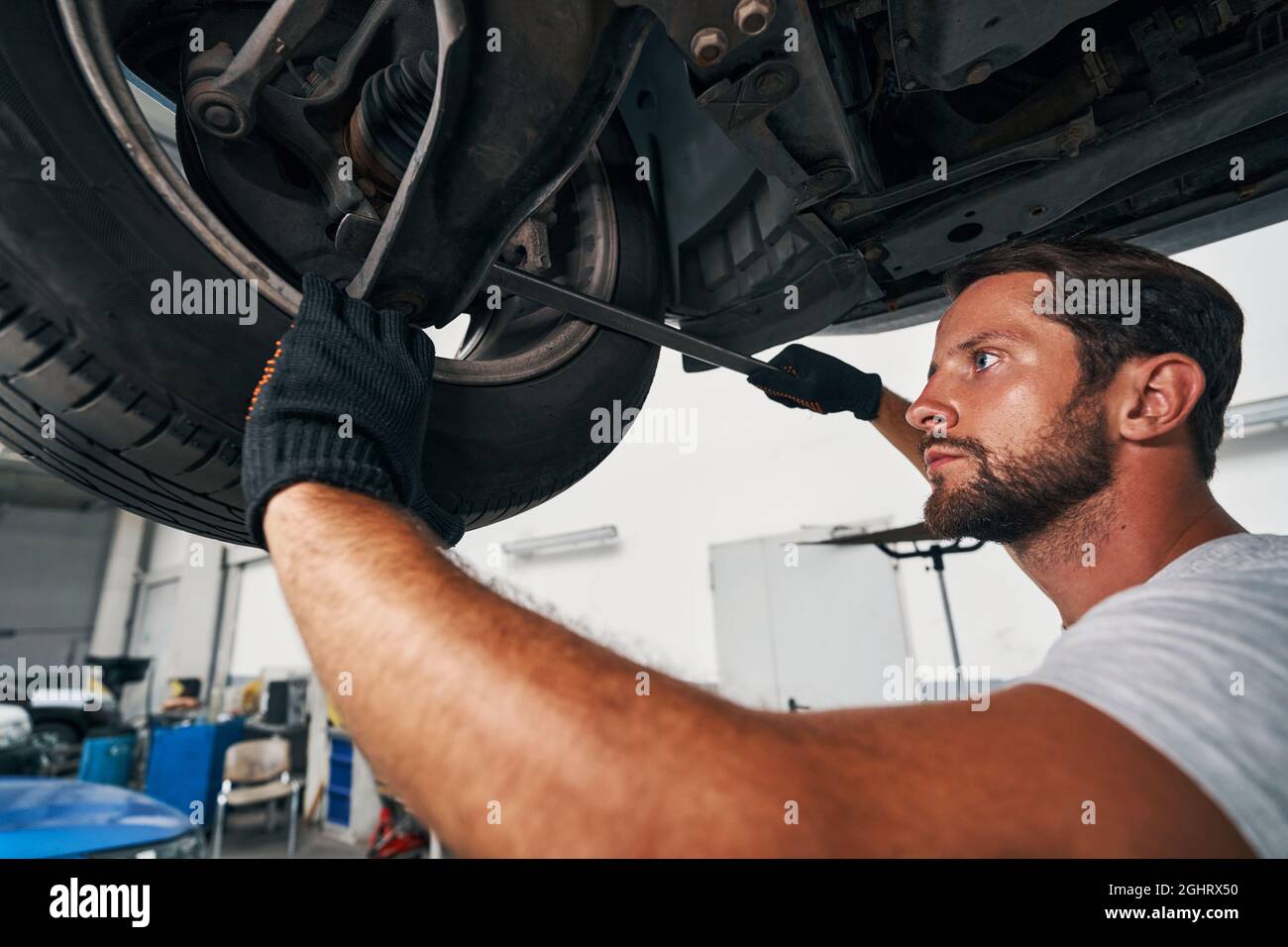 Man performing suspension system check using crowbar Stock Photo - Alamy