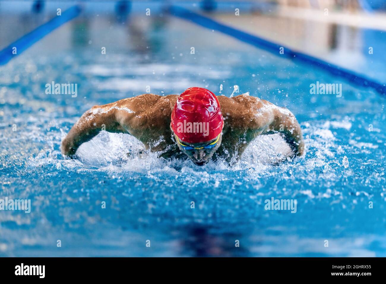Front view of professional male swimmer in red cap and goggles in ...
