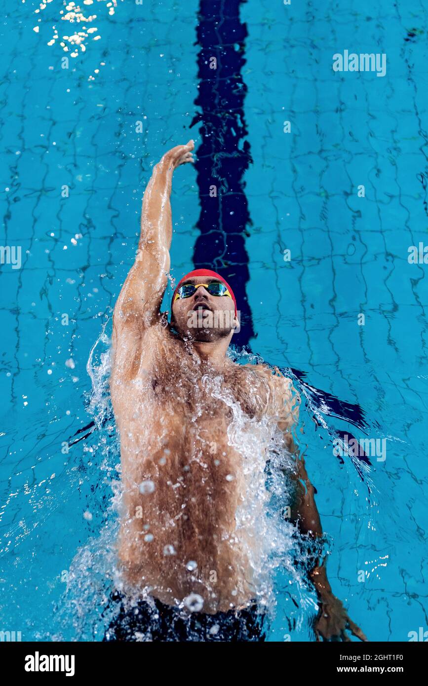 Young professional male swimmer practicing and training at pool ...