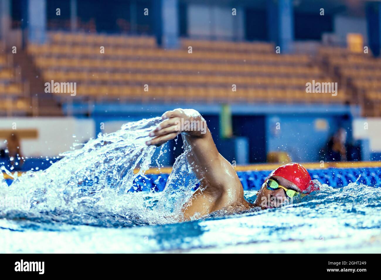 Professional male swimmer in swimming cap and goggles in motion and ...